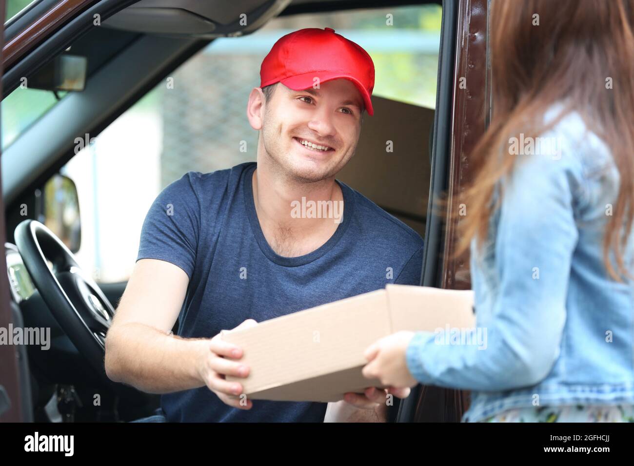 Young male deliverer giving box to woman Stock Photo - Alamy