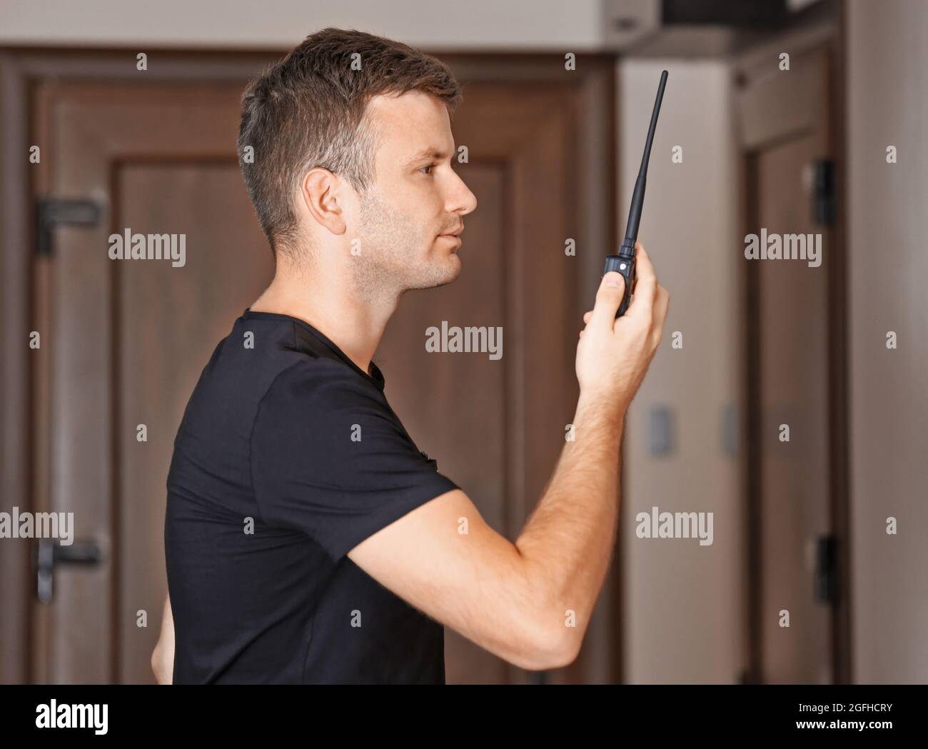 Security man standing indoors and using portable radio Stock Photo - Alamy