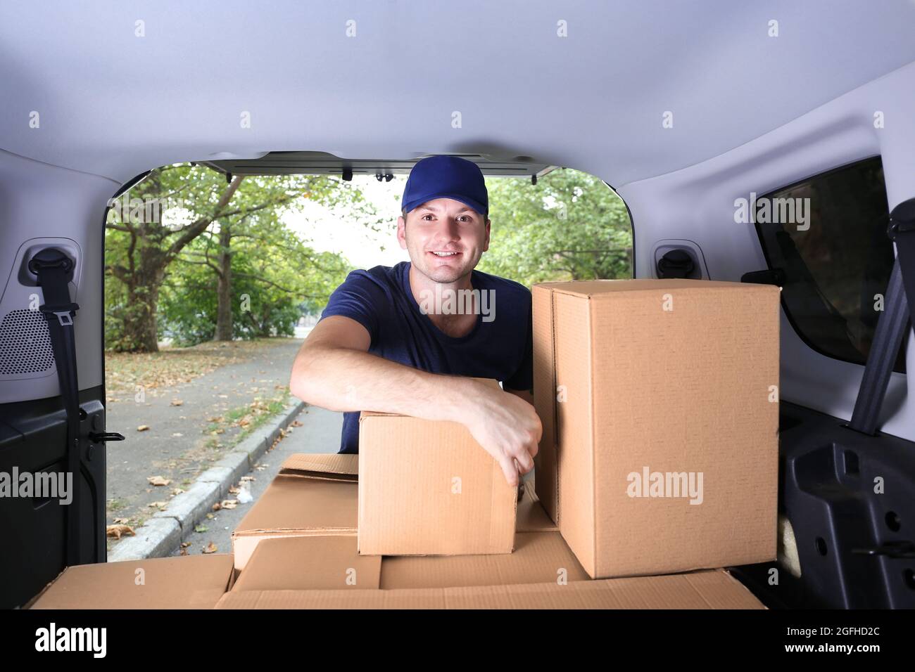 Young male deliverer loading boxes into car Stock Photo - Alamy