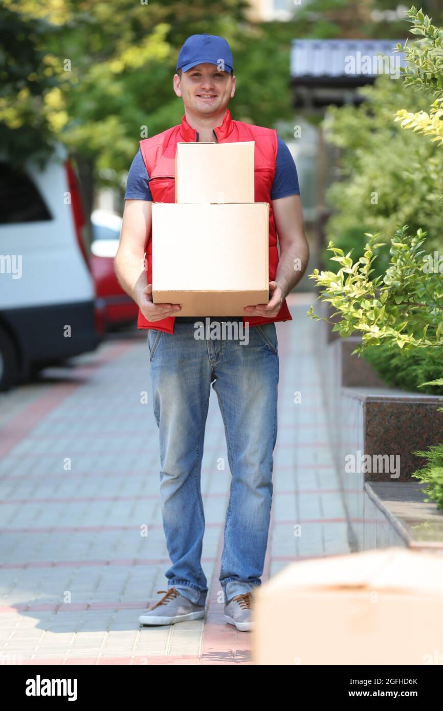 Young male deliverer with boxes outdoors Stock Photo - Alamy