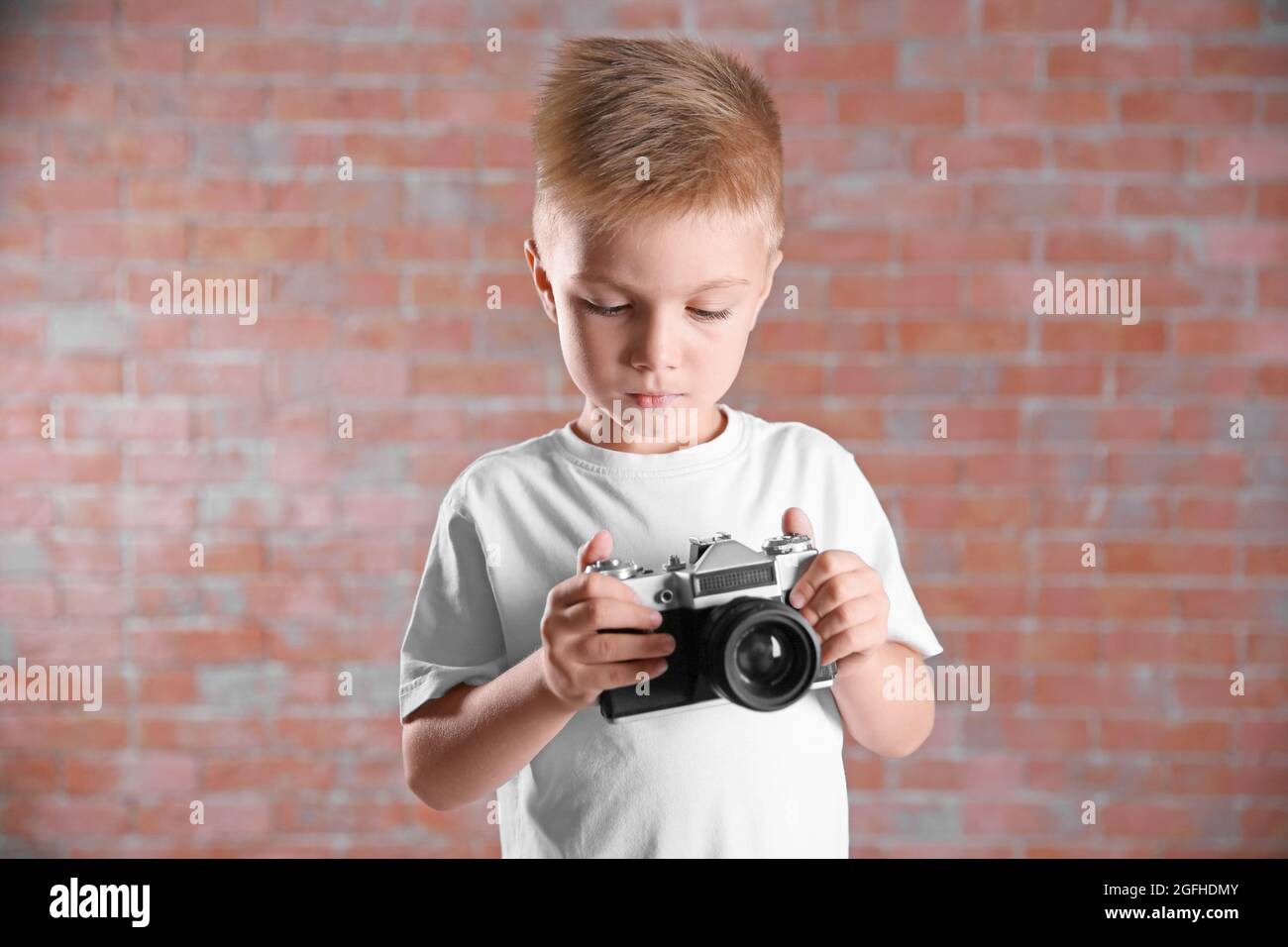 Little boy with vintage camera on brick wall background Stock Photo - Alamy