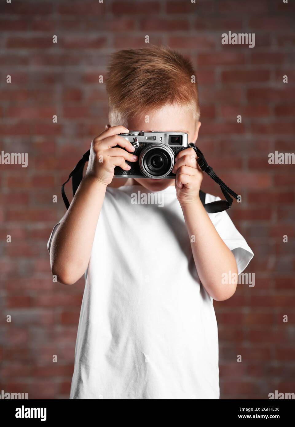 Little boy with vintage camera on brick wall background Stock Photo - Alamy