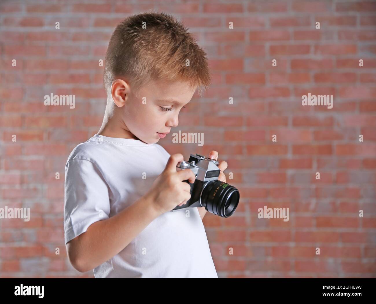 Little boy with vintage camera on brick wall background Stock Photo - Alamy