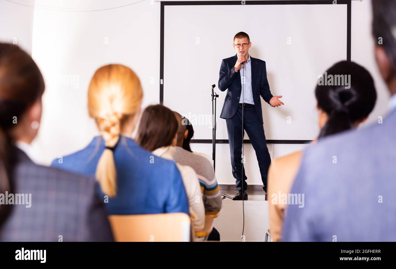 Confident man with microphone speaking at corporate business event ...