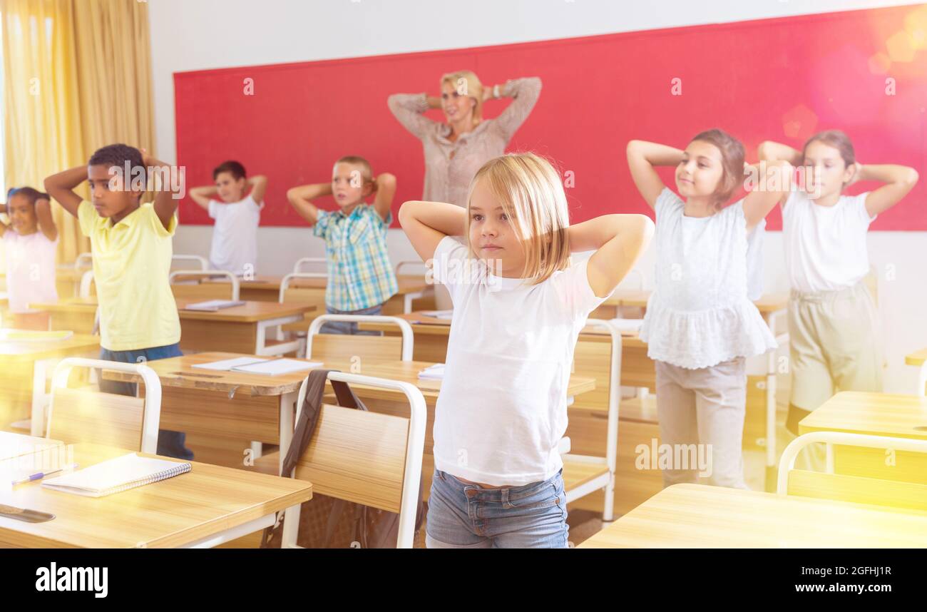 Teacher conducts gymnastics for elementary school children in classroom ...