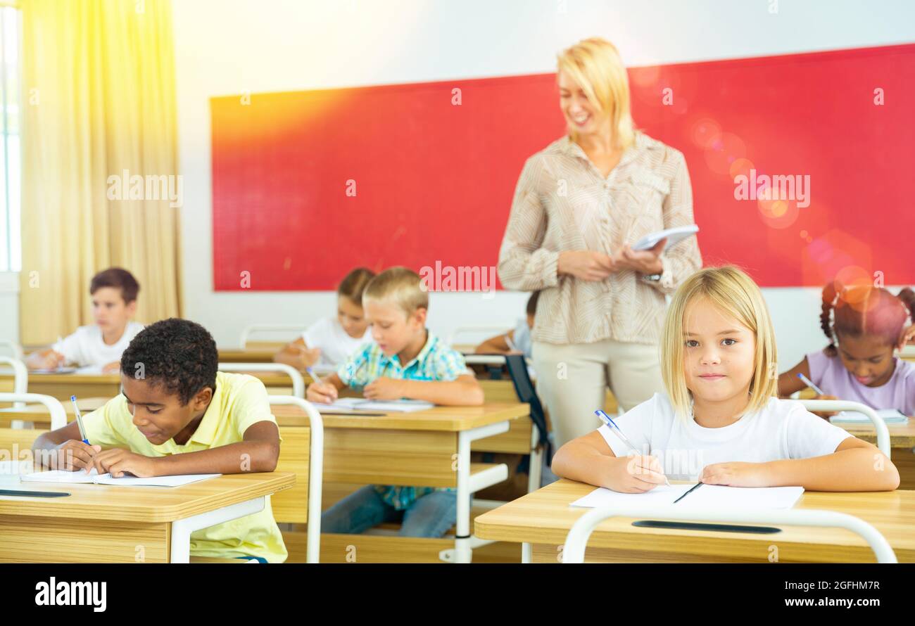 Diligent towheaded preteen girl looking at camera during lesson Stock ...