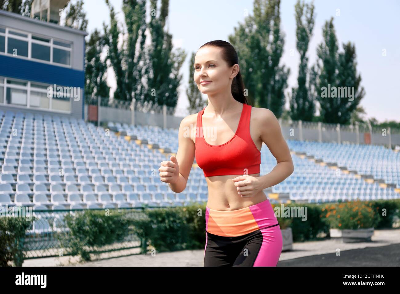 Pretty young woman running at stadium Stock Photo - Alamy