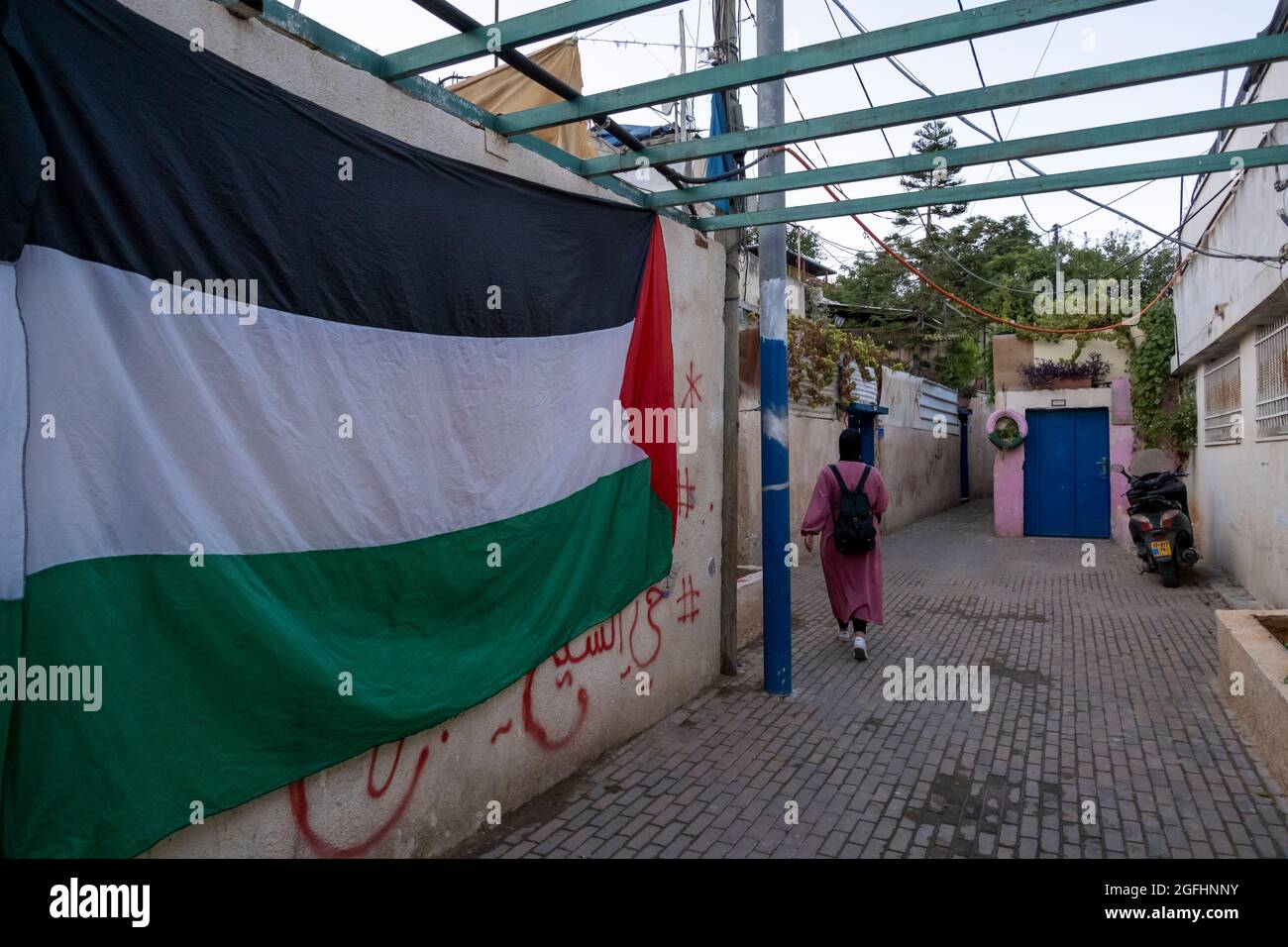 A Palestinian woman walks past a Palestinian flag which is hanged in Al ...