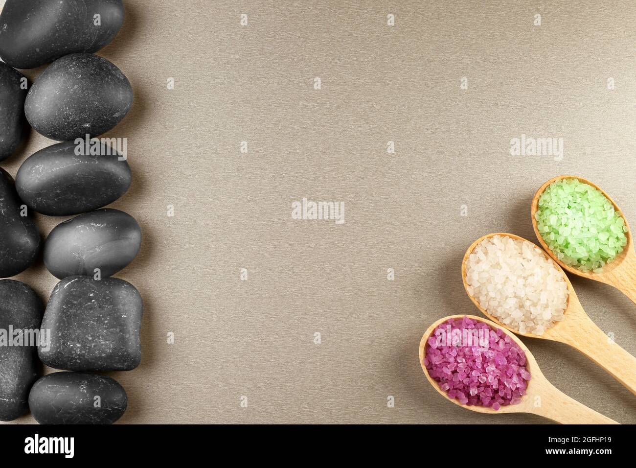 Spa stones and spoons with sea salt on color background Stock Photo - Alamy