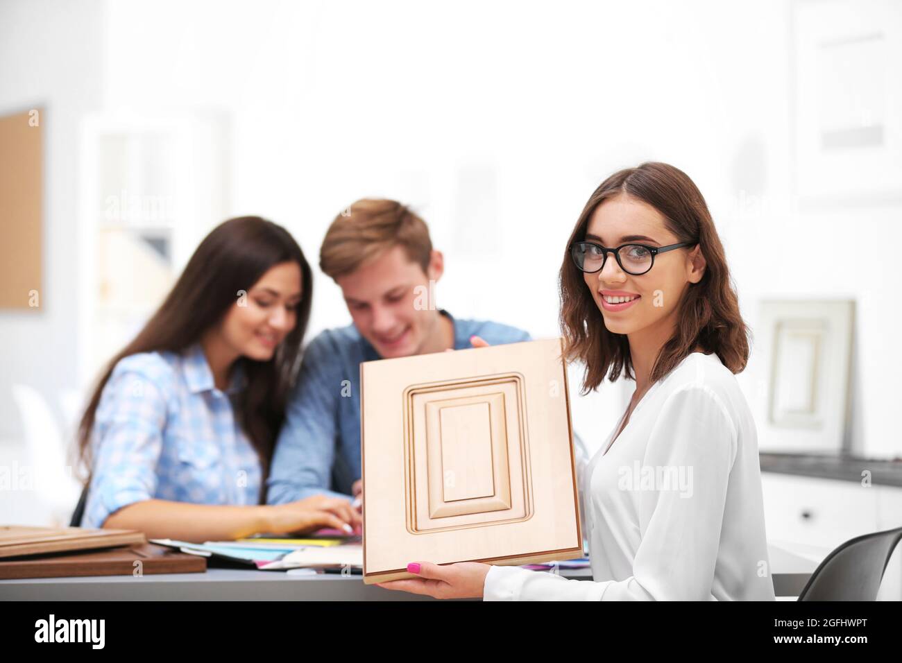 Beautiful female designer with wooden sample in office Stock Photo - Alamy