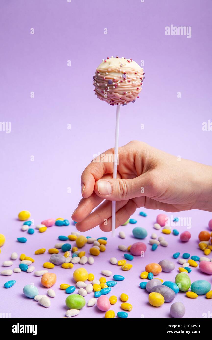 Crop person with cake pop over candies Stock Photo - Alamy