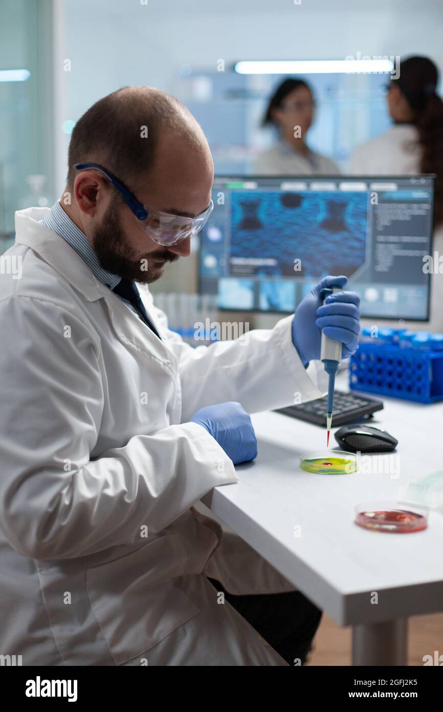 Scientist biologist man putting chemical fluid in petri dish using ...