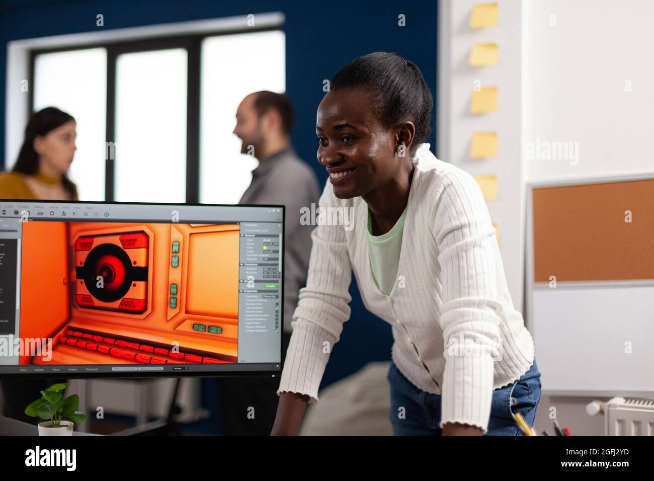 Multiethnic women designer looking at computer with dual displays ...