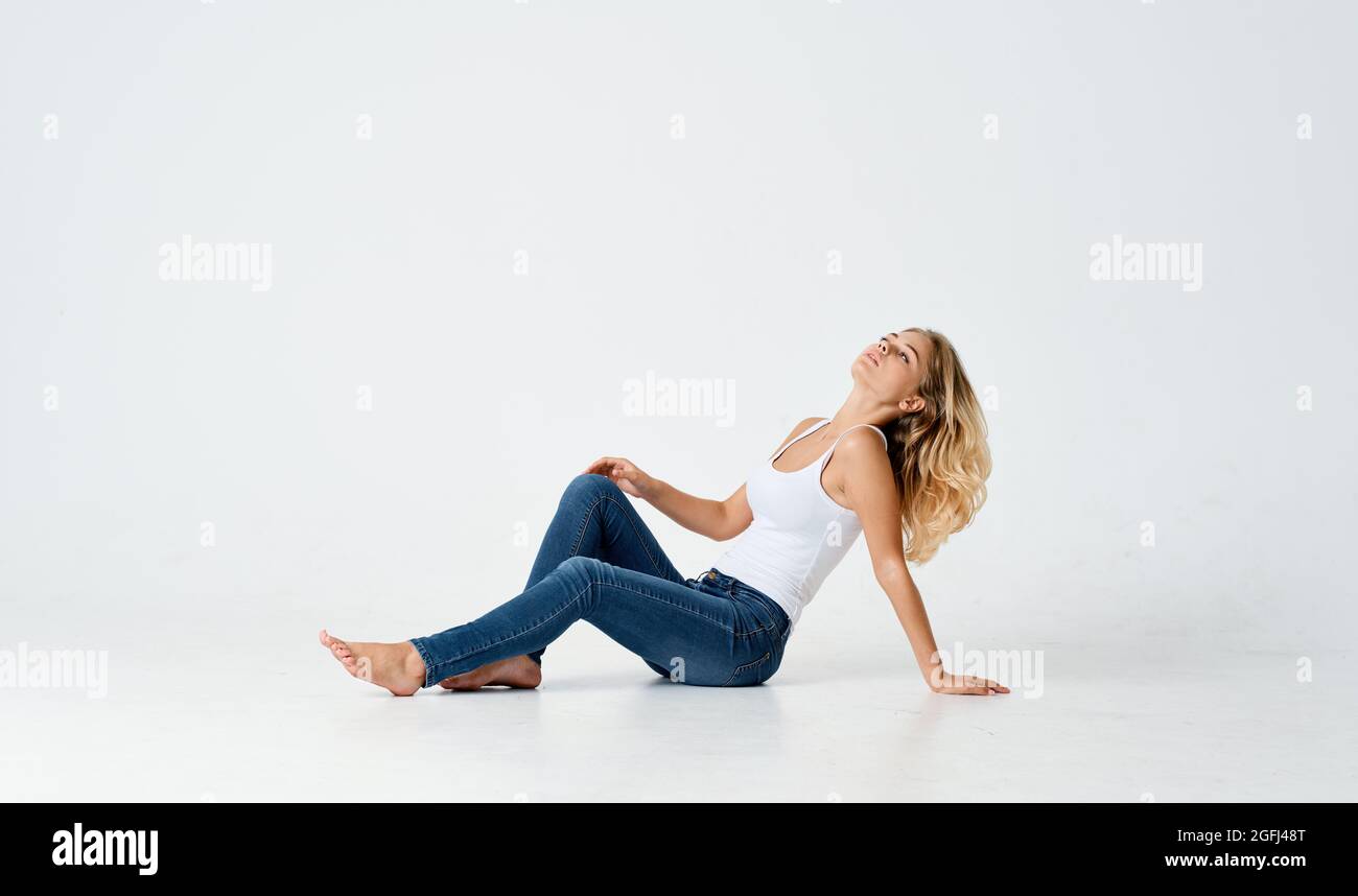 woman in jeans lies on the floor posing light background fashion Stock ...