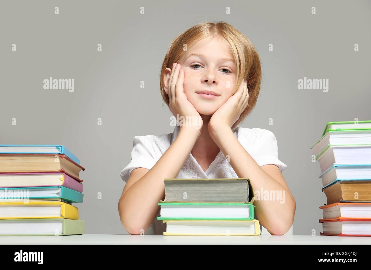 Cute girl with books on grey background Stock Photo - Alamy
