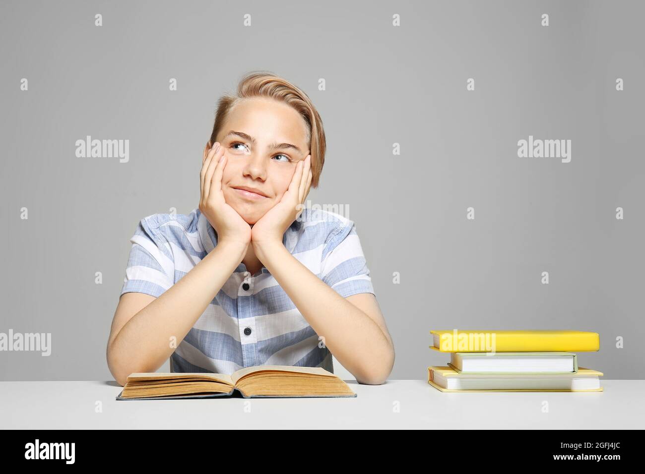 Boy making homework on grey background Stock Photo - Alamy