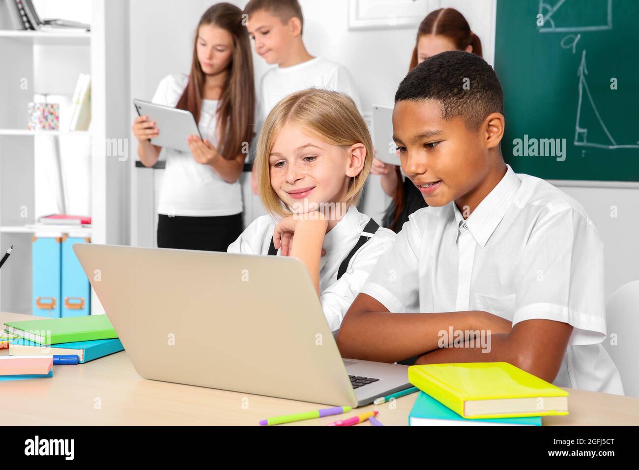 Schoolchildren sitting in classroom with laptop Stock Photo - Alamy