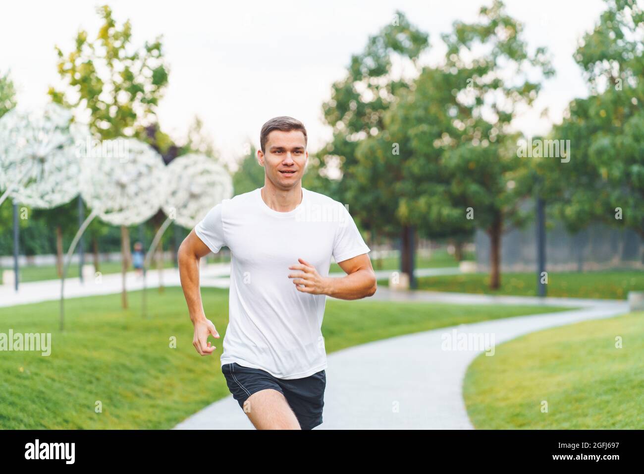 Young sports athlete man in white t-shirt run in the morning in modern ...