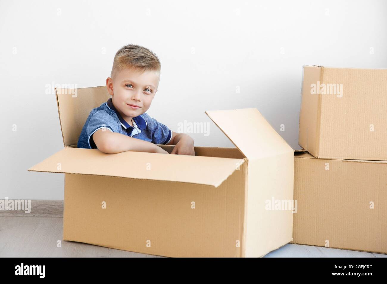 Little boy playing with cardboard boxes on white wall background Stock ...