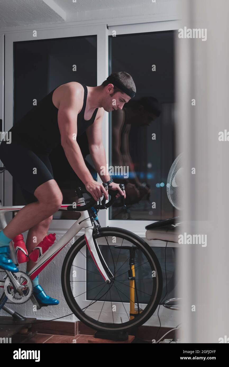 Man cycling on the machine trainer he is exercising in the home at ...