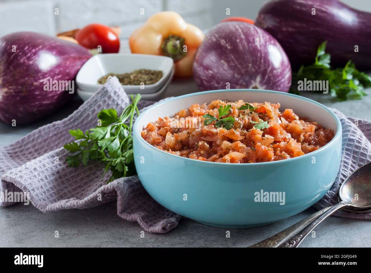 Eggplant caviar in blue bowl and fresh vegetables on background Stock ...