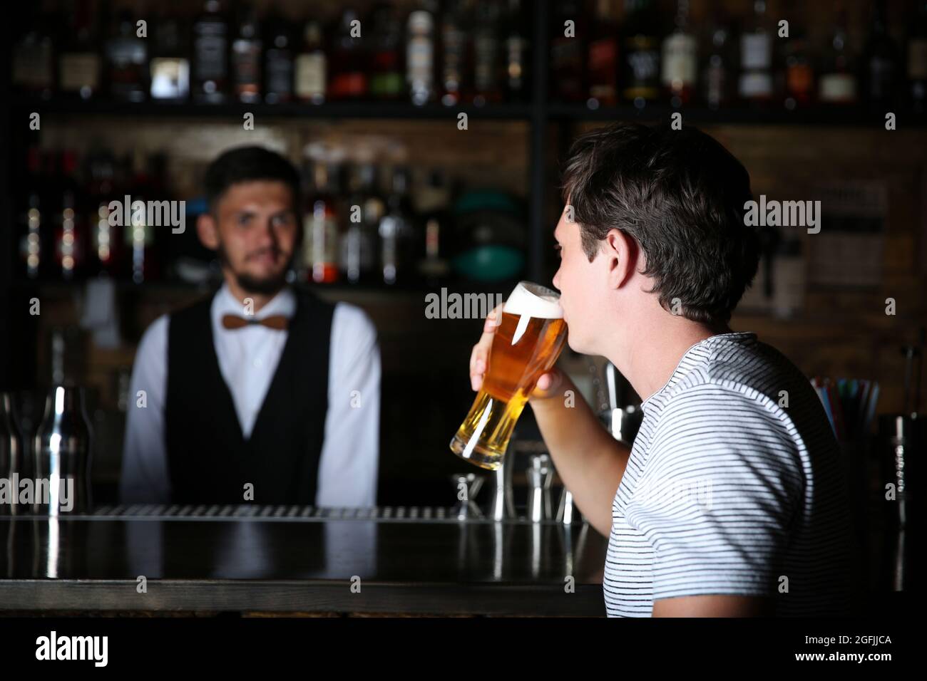 Man drinking beer at bar counter Stock Photo - Alamy