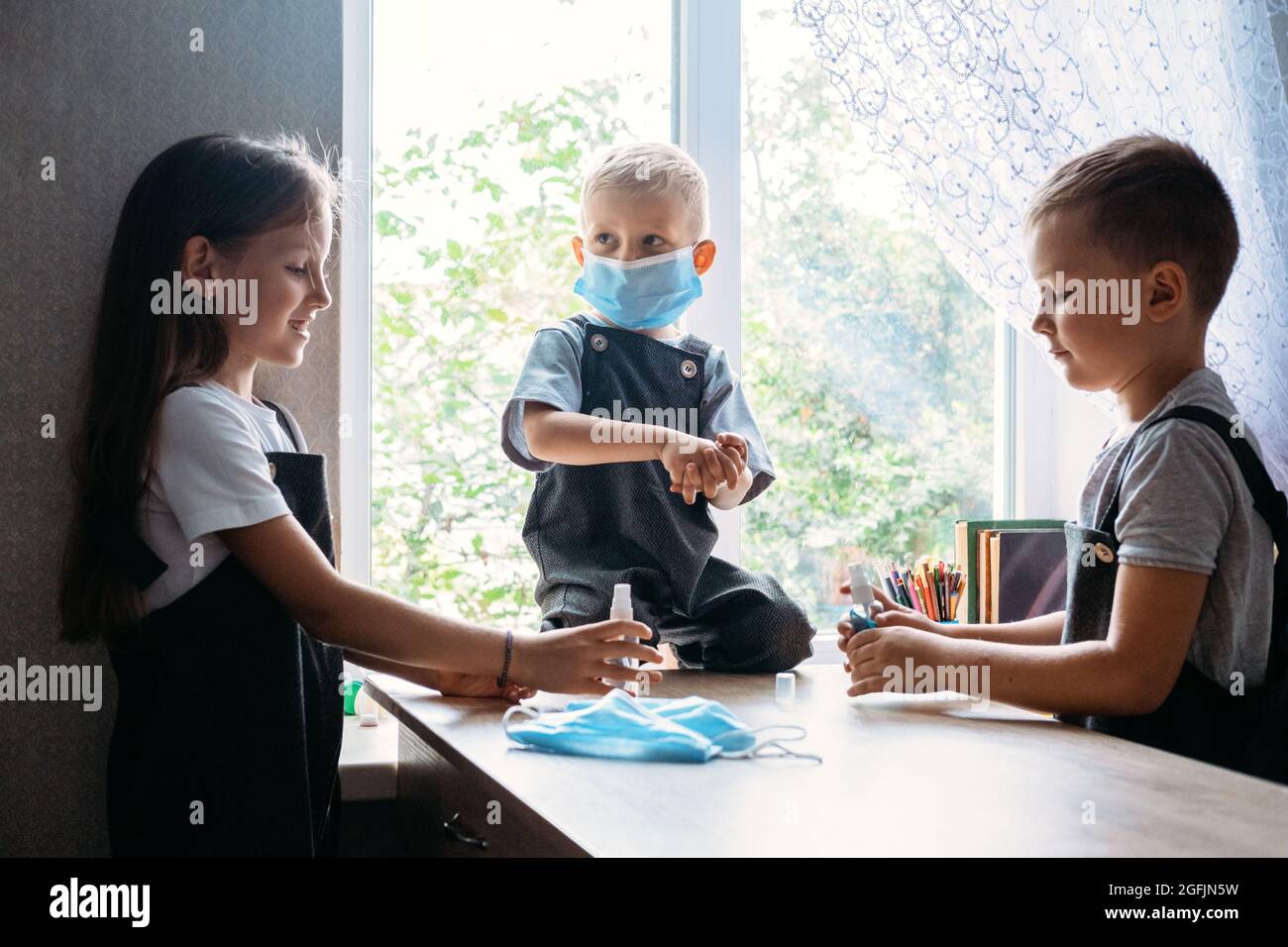Back To School Safety. Schoolkids wearing masks and using antiseptic in ...