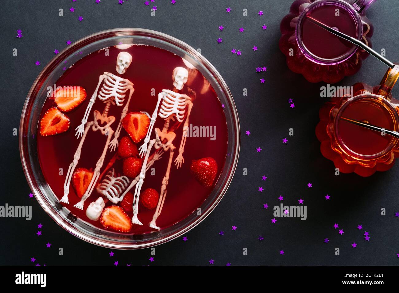 Halloween drink with strawberry and skeletons on dark background. Flat ...