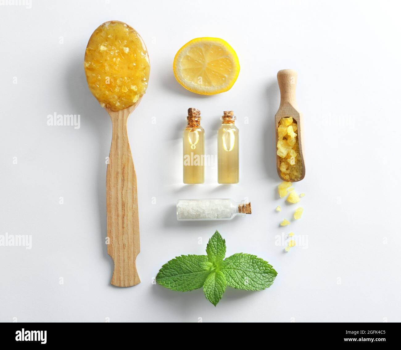 Wooden spoon with scrub, lemon slice, mint, sea salt and bottles of oil ...