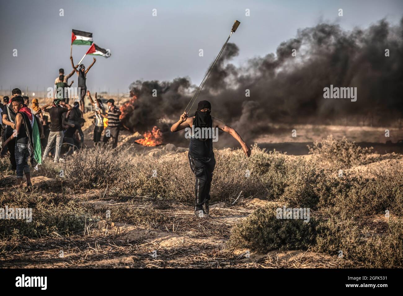 A Palestinian demonstrator uses a slingshot to throw stones at the ...