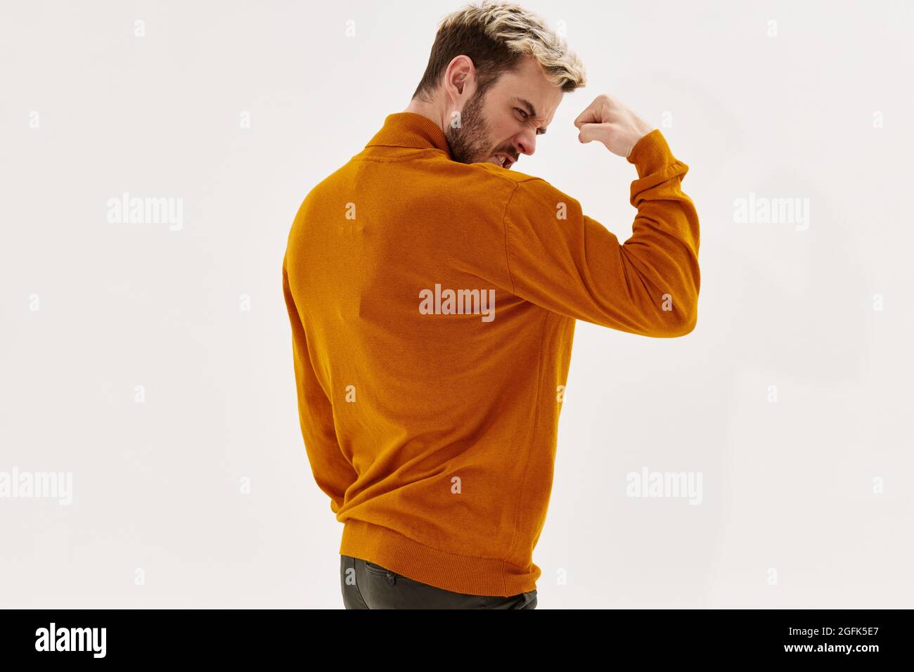 strong man shows his arm muscles and orange sweater blond Copy Space ...