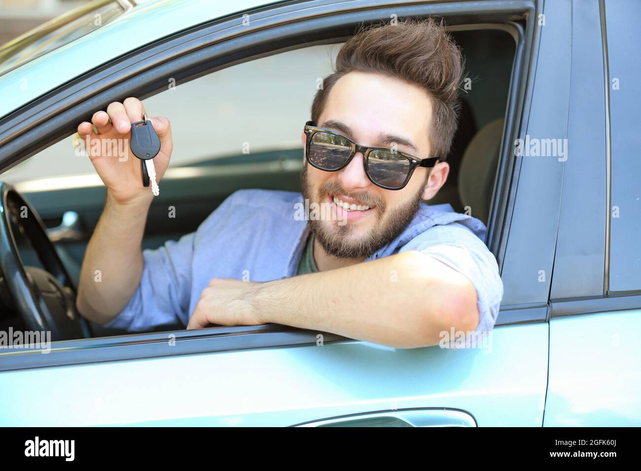 Successful young driver showing car key through open window Stock Photo ...