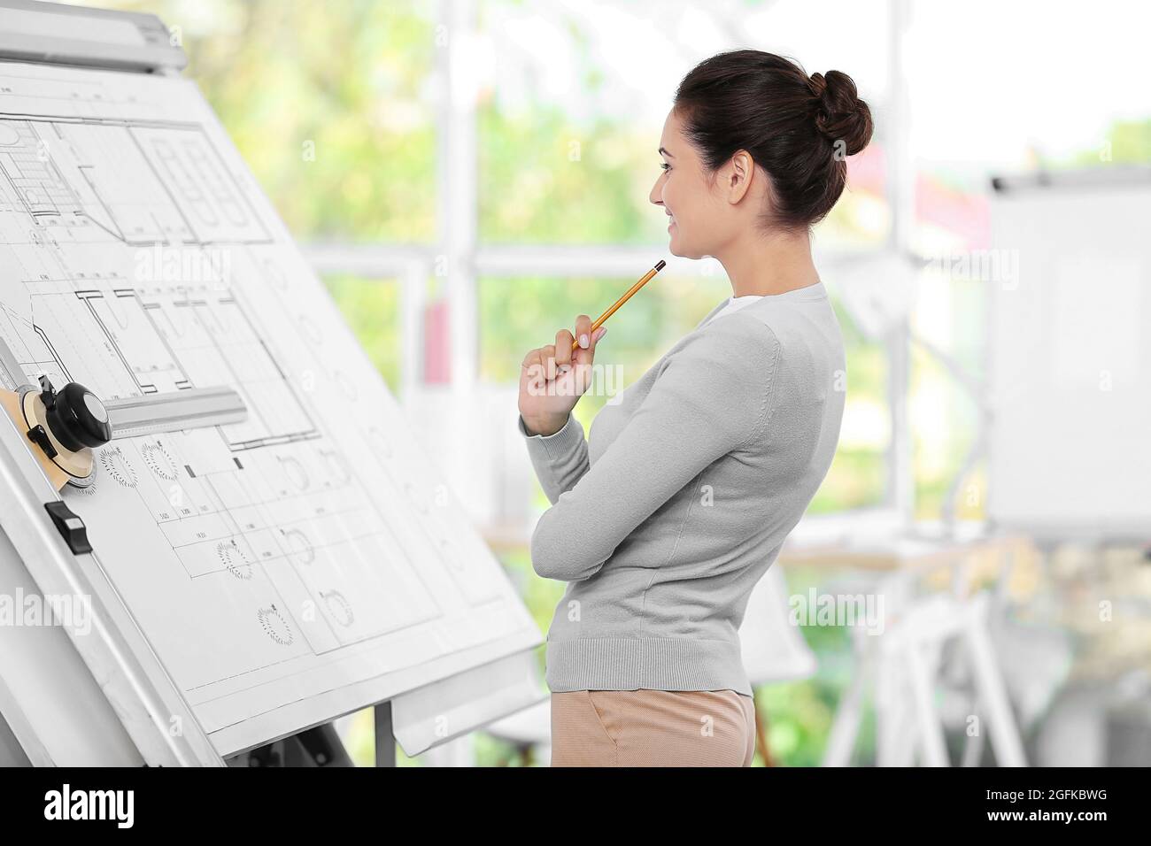 Young female engineer working with project on drawing board in office ...