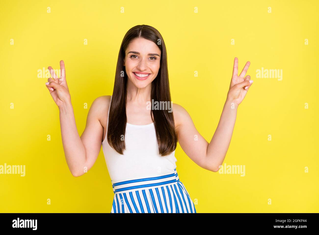 Portrait of attractive cheerful girl showing double v-sign having fun ...
