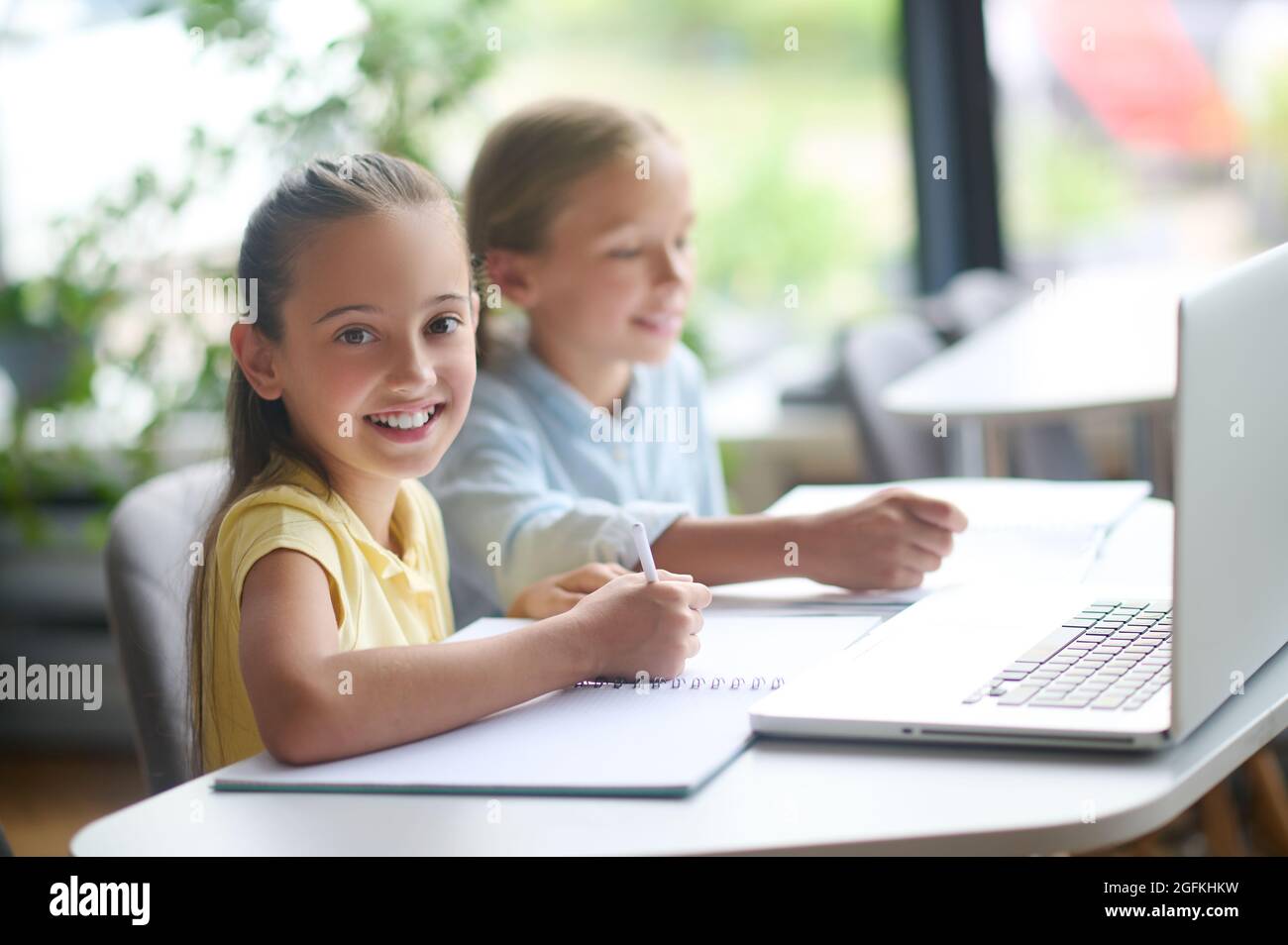 Girl with a pen and her classmate sitting at the desk Stock Photo - Alamy