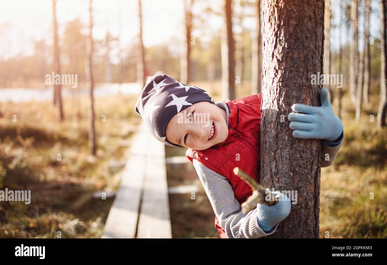 Cute boy in the forest hugging a tree's trunk Stock Photo - Alamy