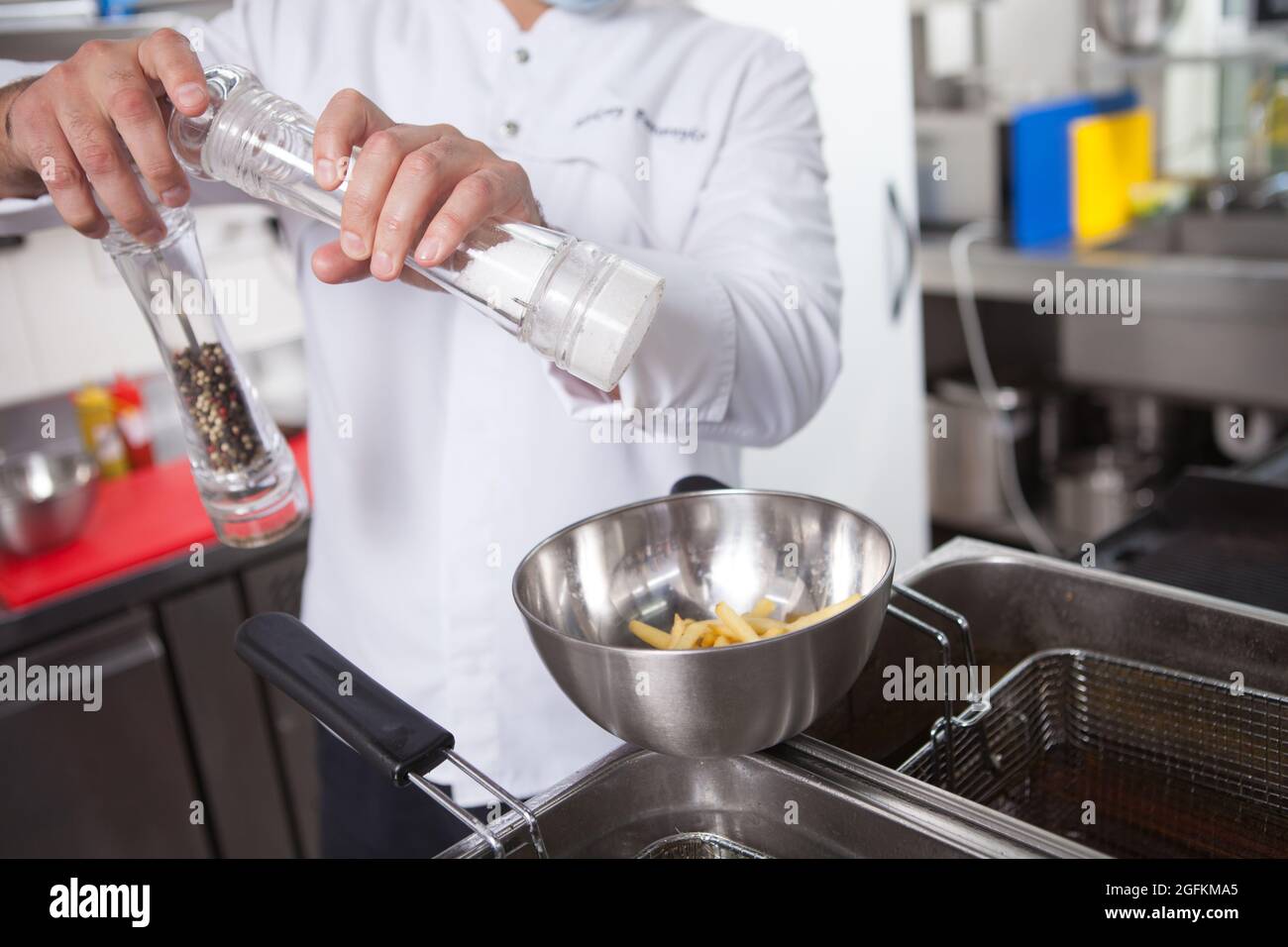 Unrecognizable chef salting frehcn fries at the kitchen Stock Photo - Alamy