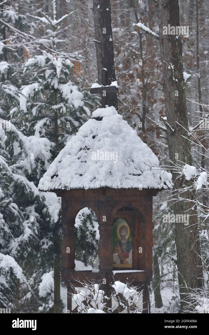 a wooden wayside shrine in the forest, covered with snow in winter ...