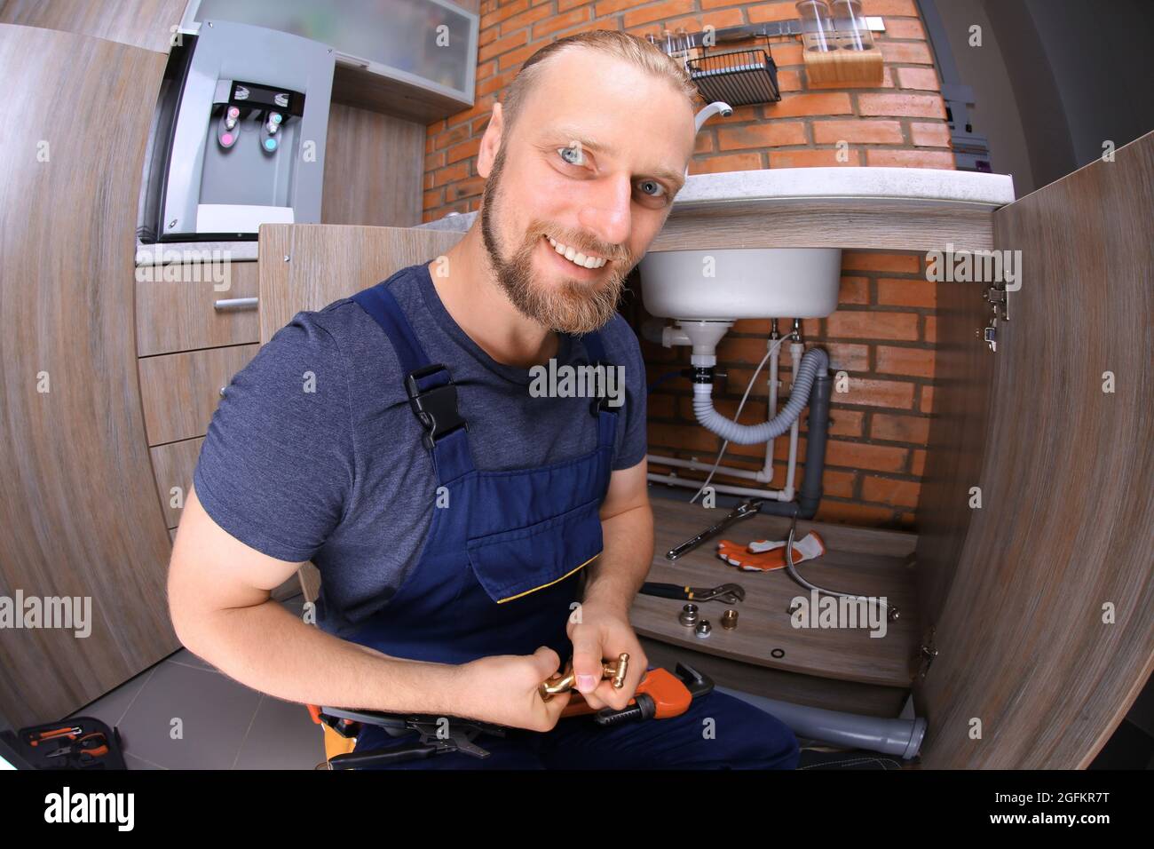 Funny plumber repairing sink pipes in kitchen Stock Photo - Alamy