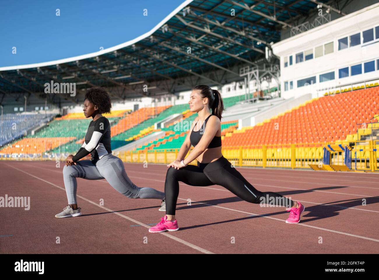 Diverse sportswomen in sportswear lunging on track before track and ...