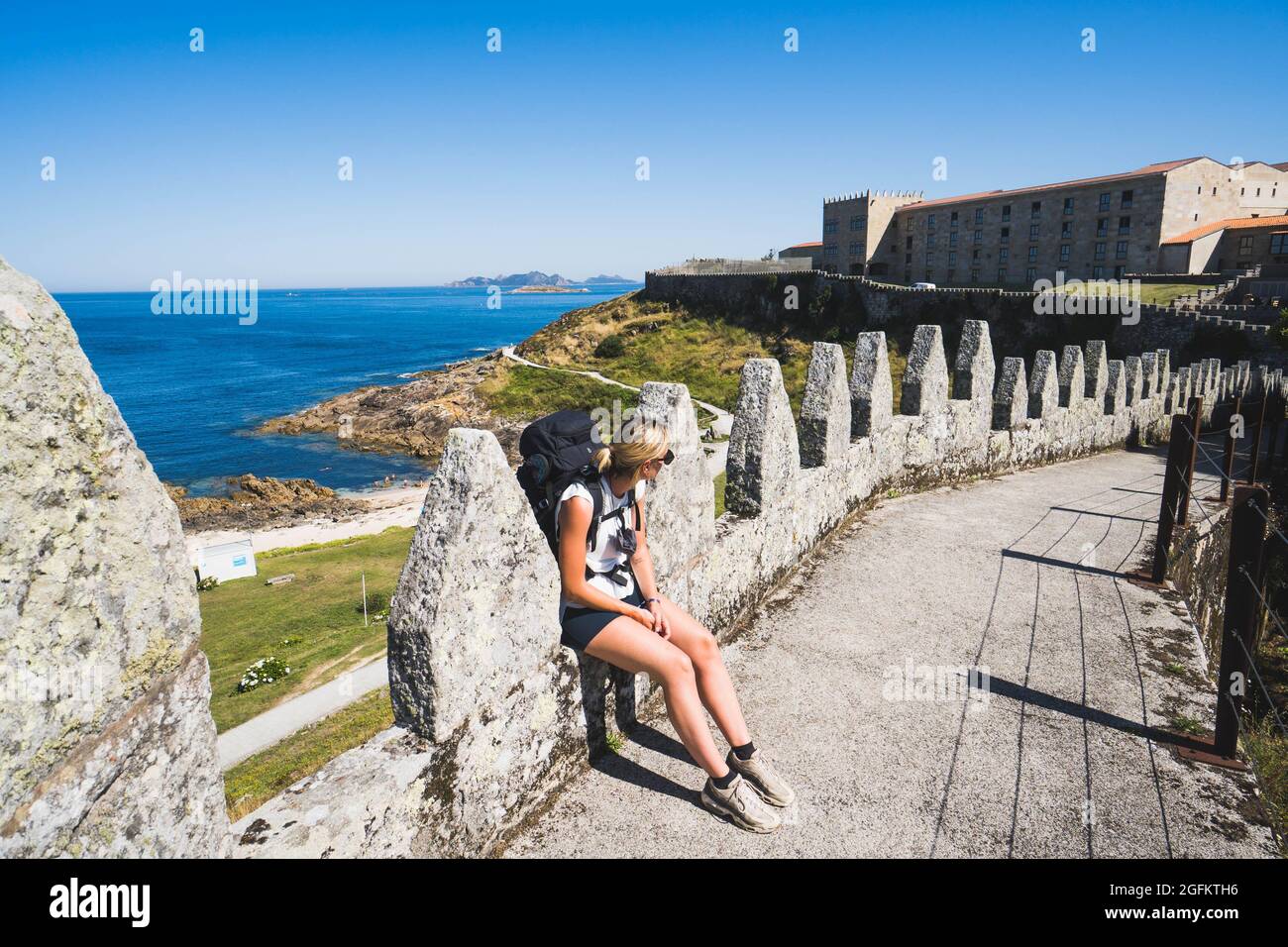 pilgrim woman sitting on the wall of a castle against the sea Stock ...