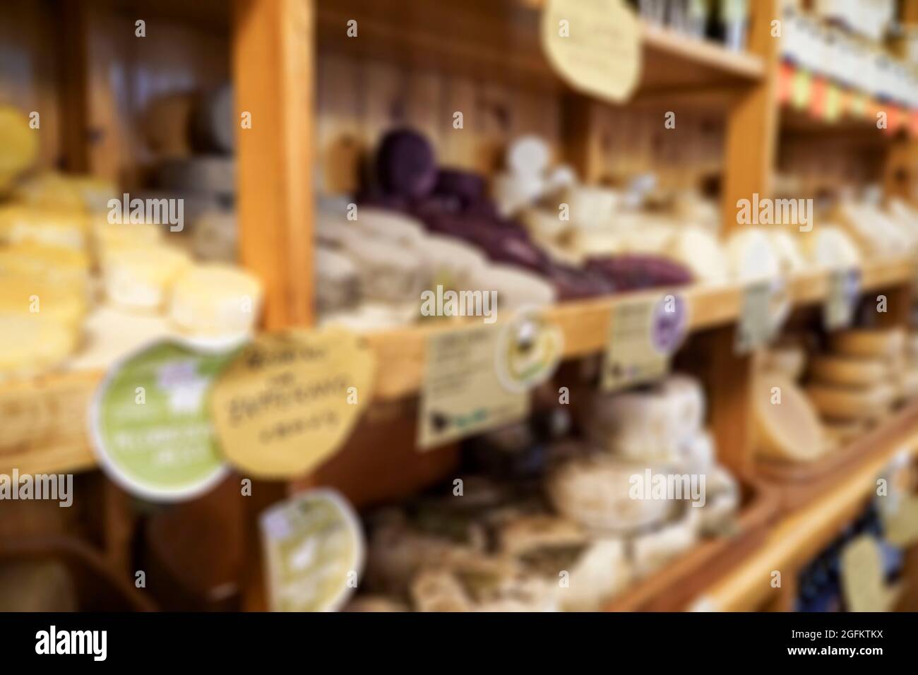 blurred background with variety of cheeses on shelves in a supermarket ...