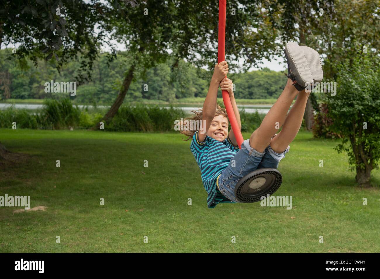 Happy boy swinging on rope on playground in weekend morning Stock Photo ...