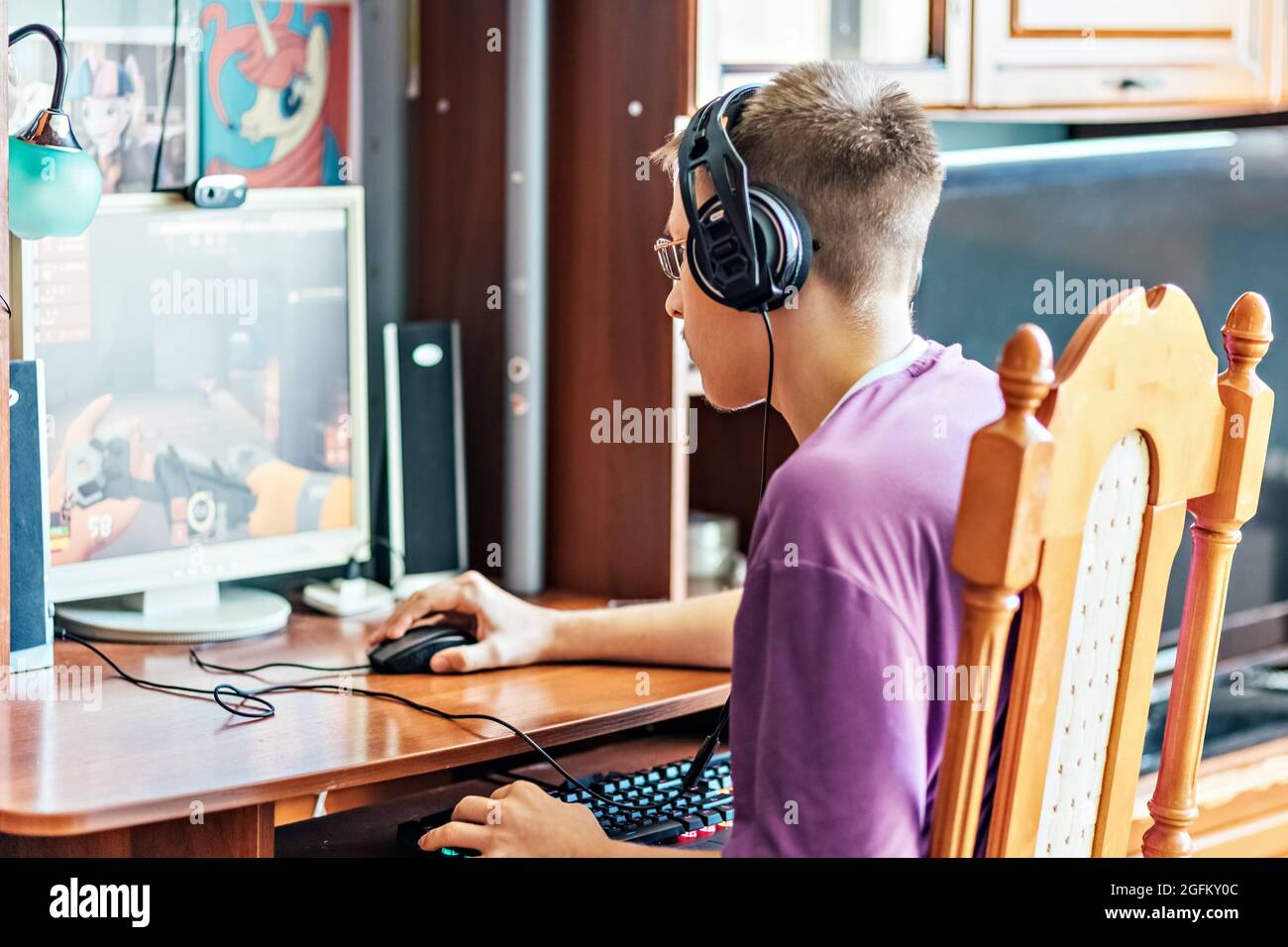 A teenage boy, a young man playing video games on a computer, using ...