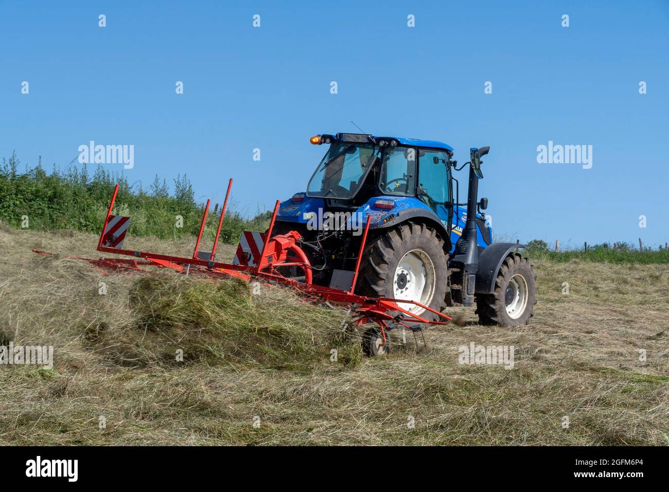Tractor cutting hay in a sunny field, showing agricultural practices in ...