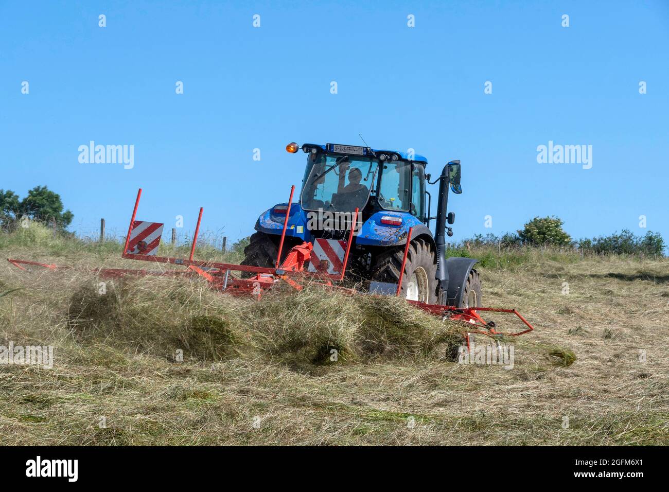 Tractor cutting hay in a sunny field, showing agricultural practices in ...