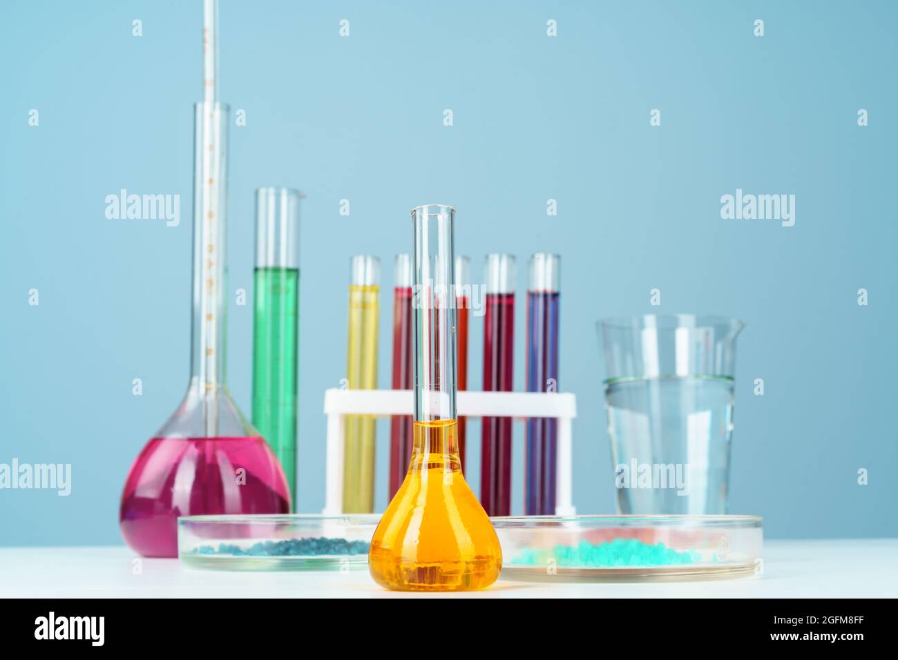 Chemical laboratory glassware with various colored liquids on table ...