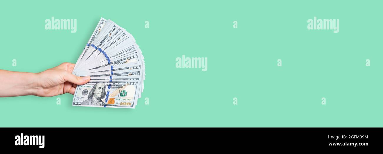 Hand holding a big stack of banknotes isolated on light green ...