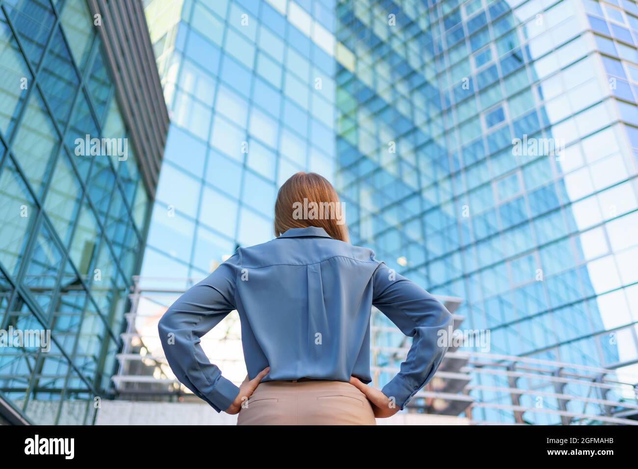 Back view of successful manager looking at business building of modern ...