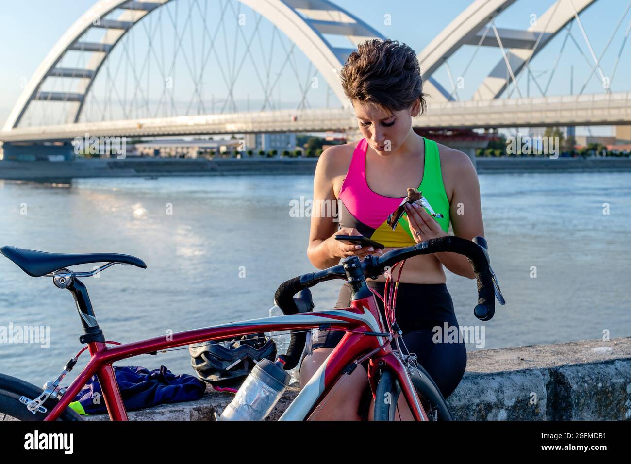 Happy young woman cyclist eating an energy bar, refreshing and having a ...